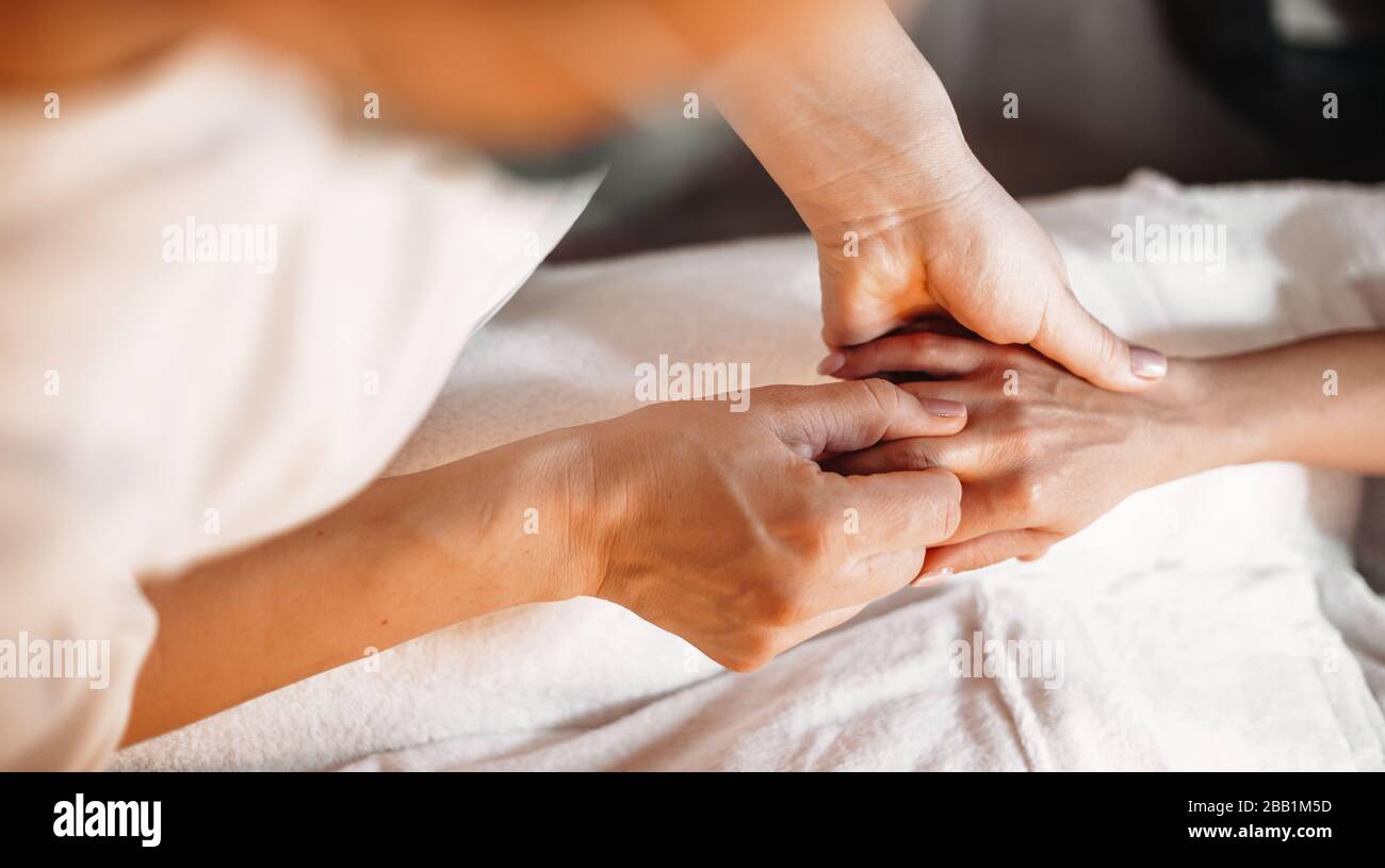 Caucasian spa worker massaging client's fingers during a hand massage ...