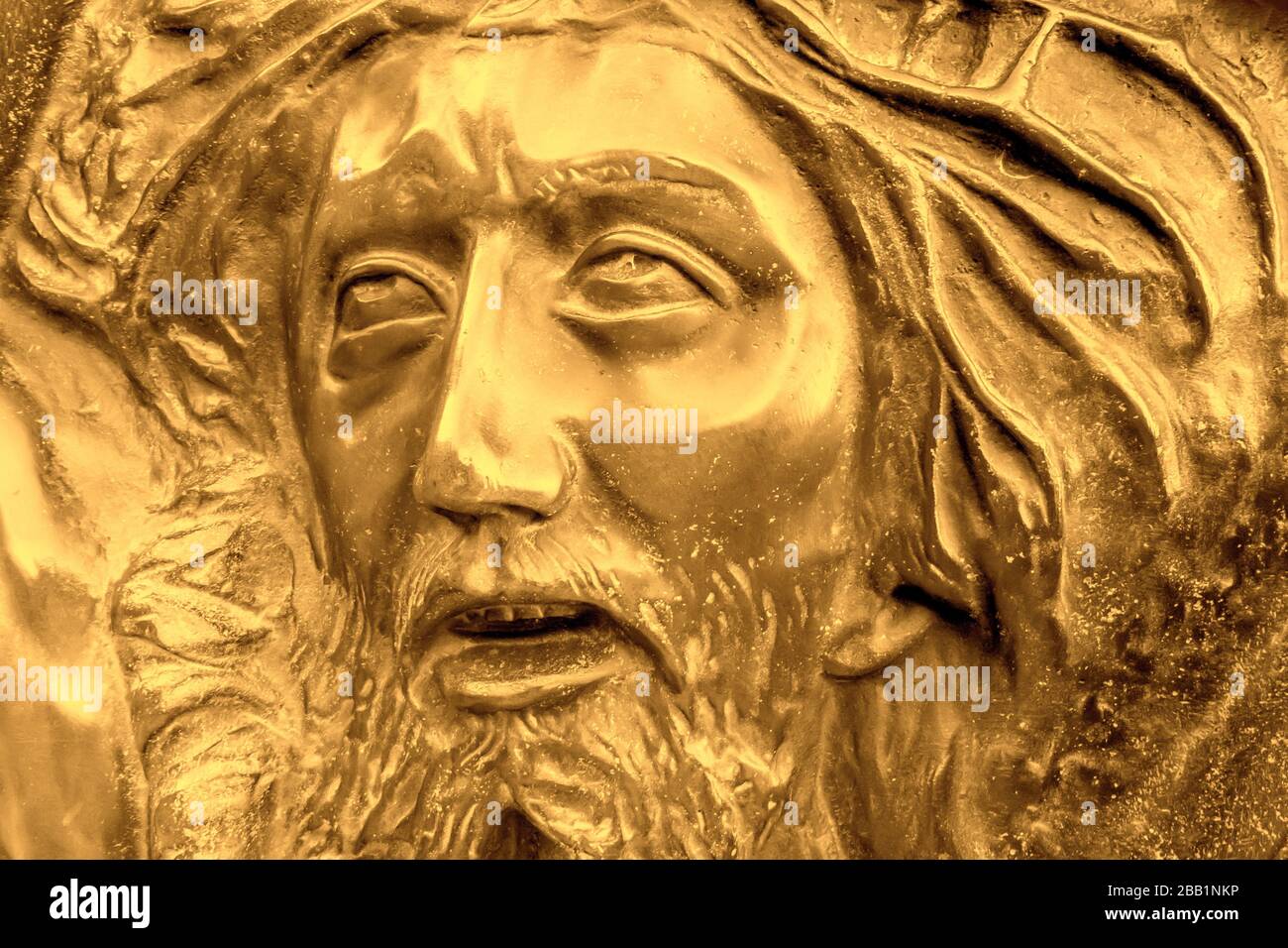 Golden bas-relief of Jesus crowned with thorns. High golden relief face ...