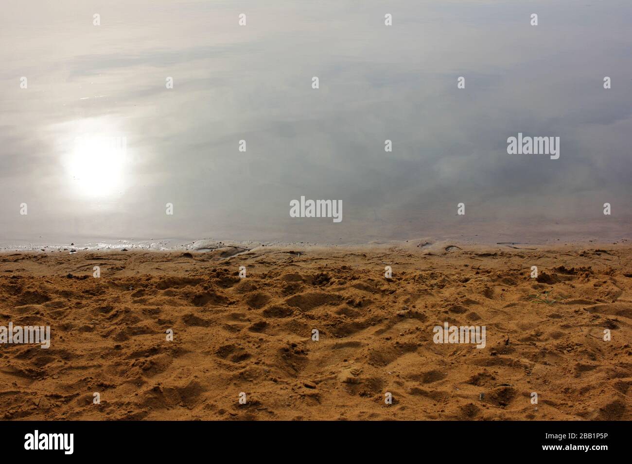 empty-yellow-sandy-beach-dark-river-water-and-sun-reflection