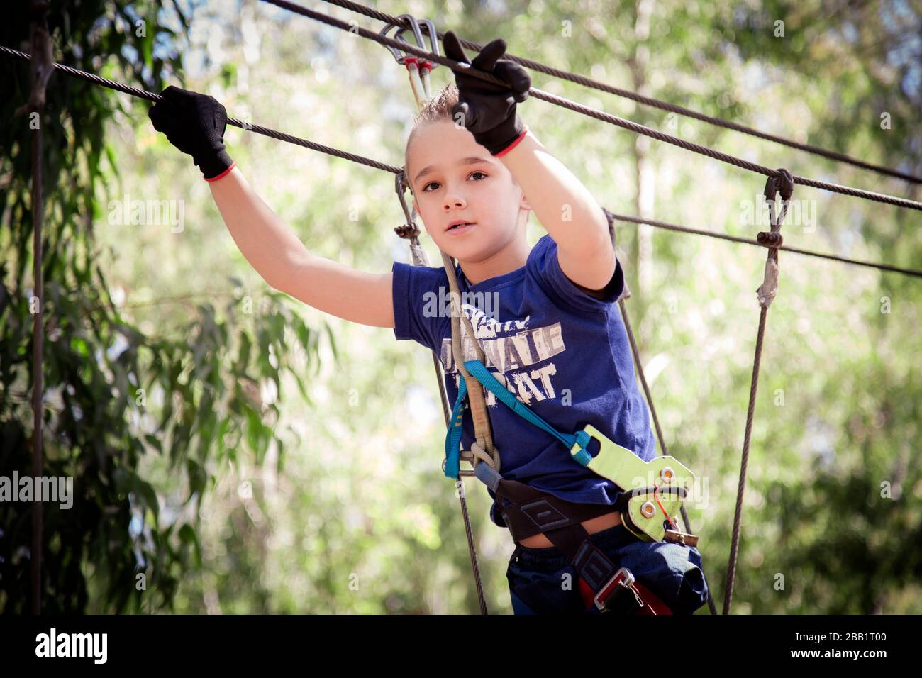 Color photo of a young beautiful boy climbing on suspended ropes or ...