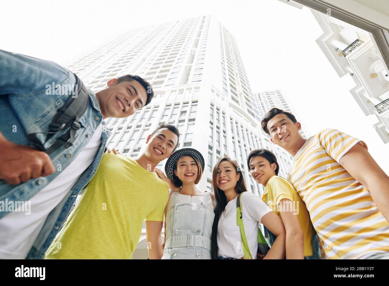 Group of cheerful students standing on the street and looking down at ...