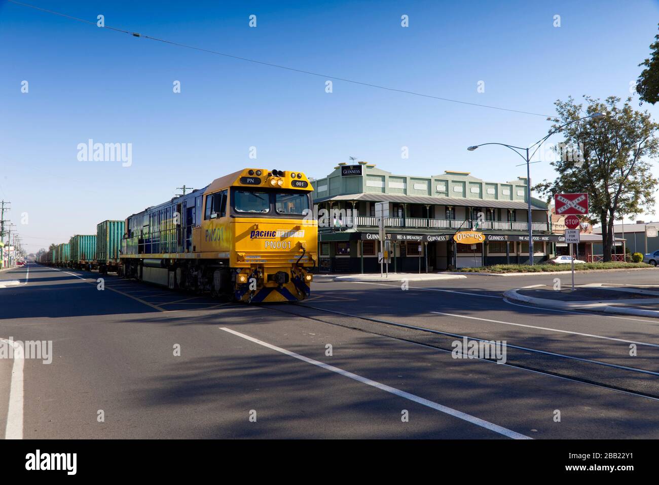 Pacific National freight train passing queenslander style hotel in ...