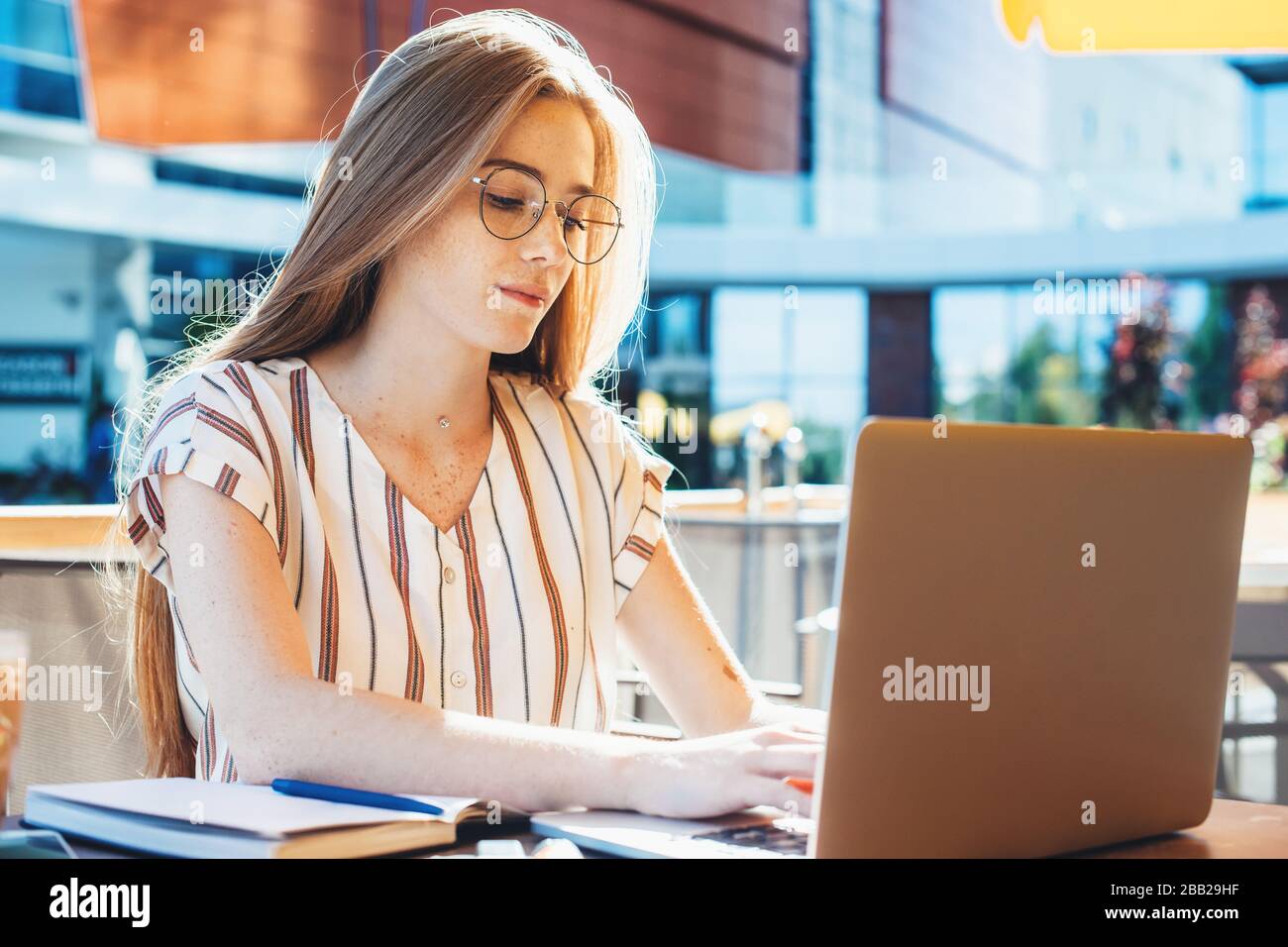 Red haired caucasian woman with freckles and glasses typing something ...