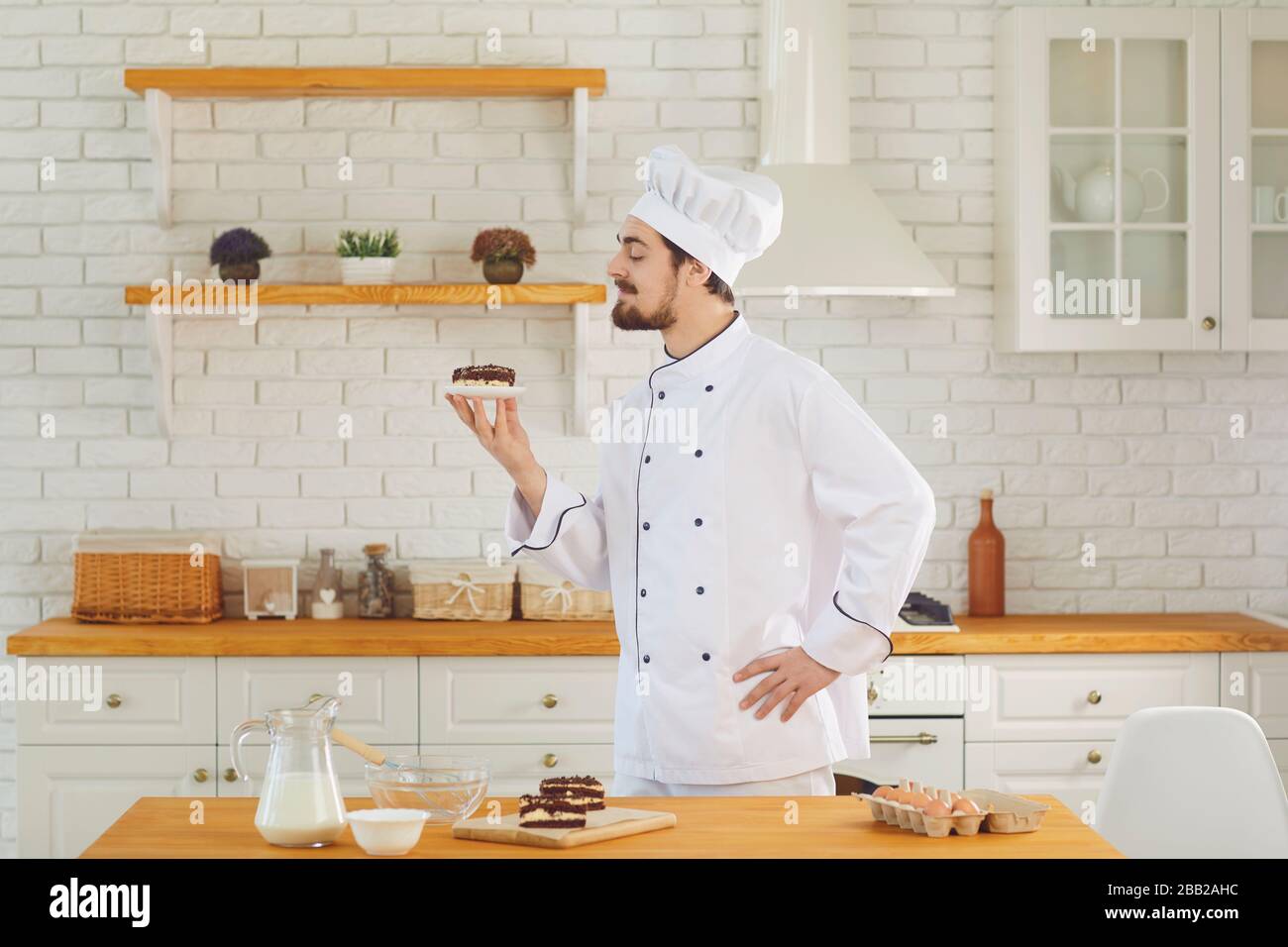 Confectioner man smiles while standing with cake in his hands at the ...
