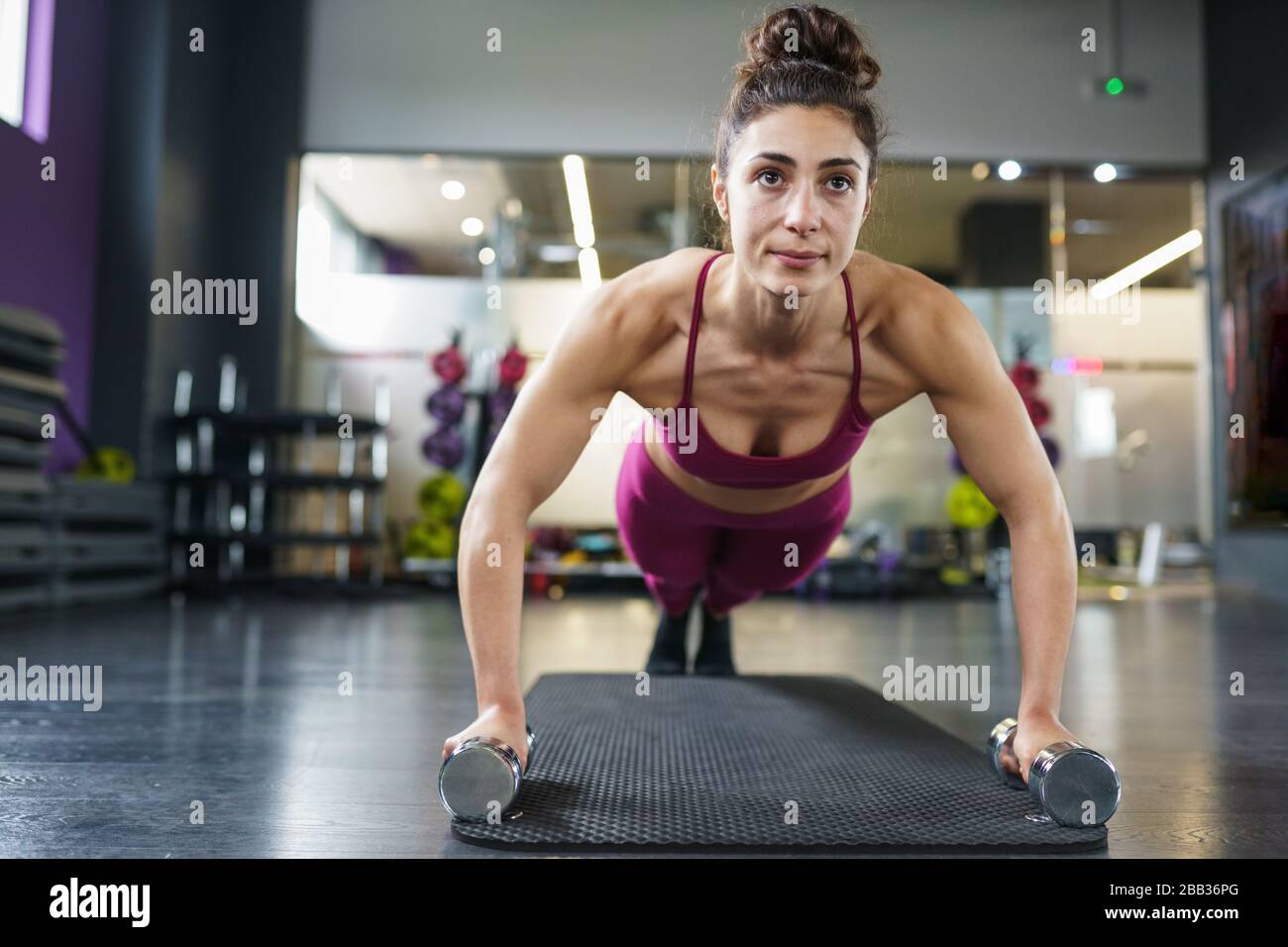 Woman doing push-ups exercise with dumbbell in a fitness workout Stock ...