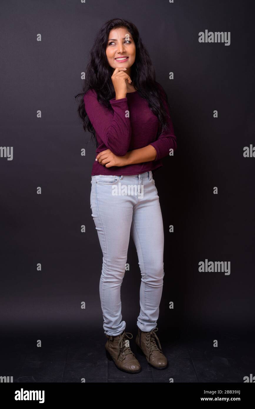 Full body shot of happy young beautiful Indian woman thinking Stock ...