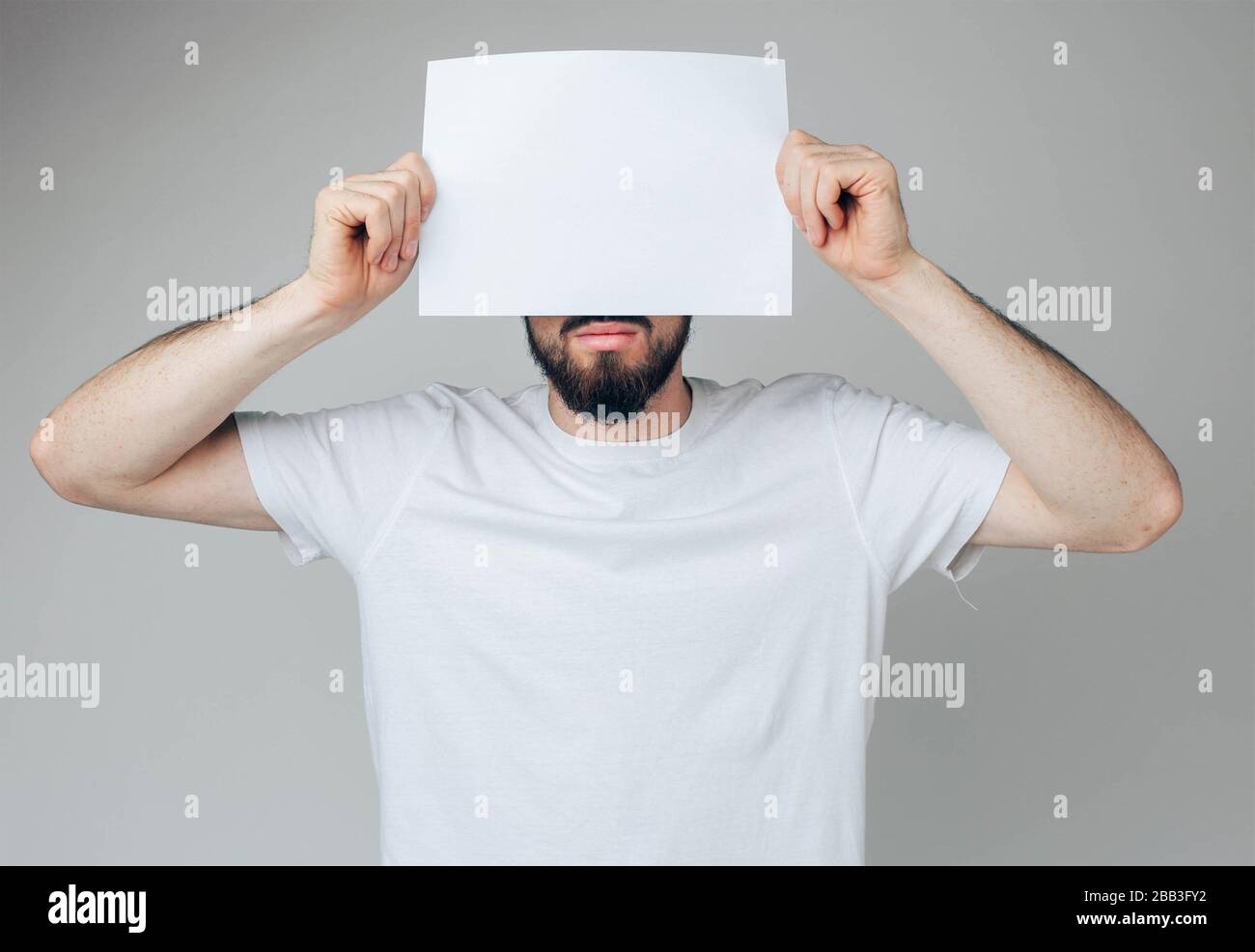 Young man isolated over background. Bearded guy cover part of face with ...