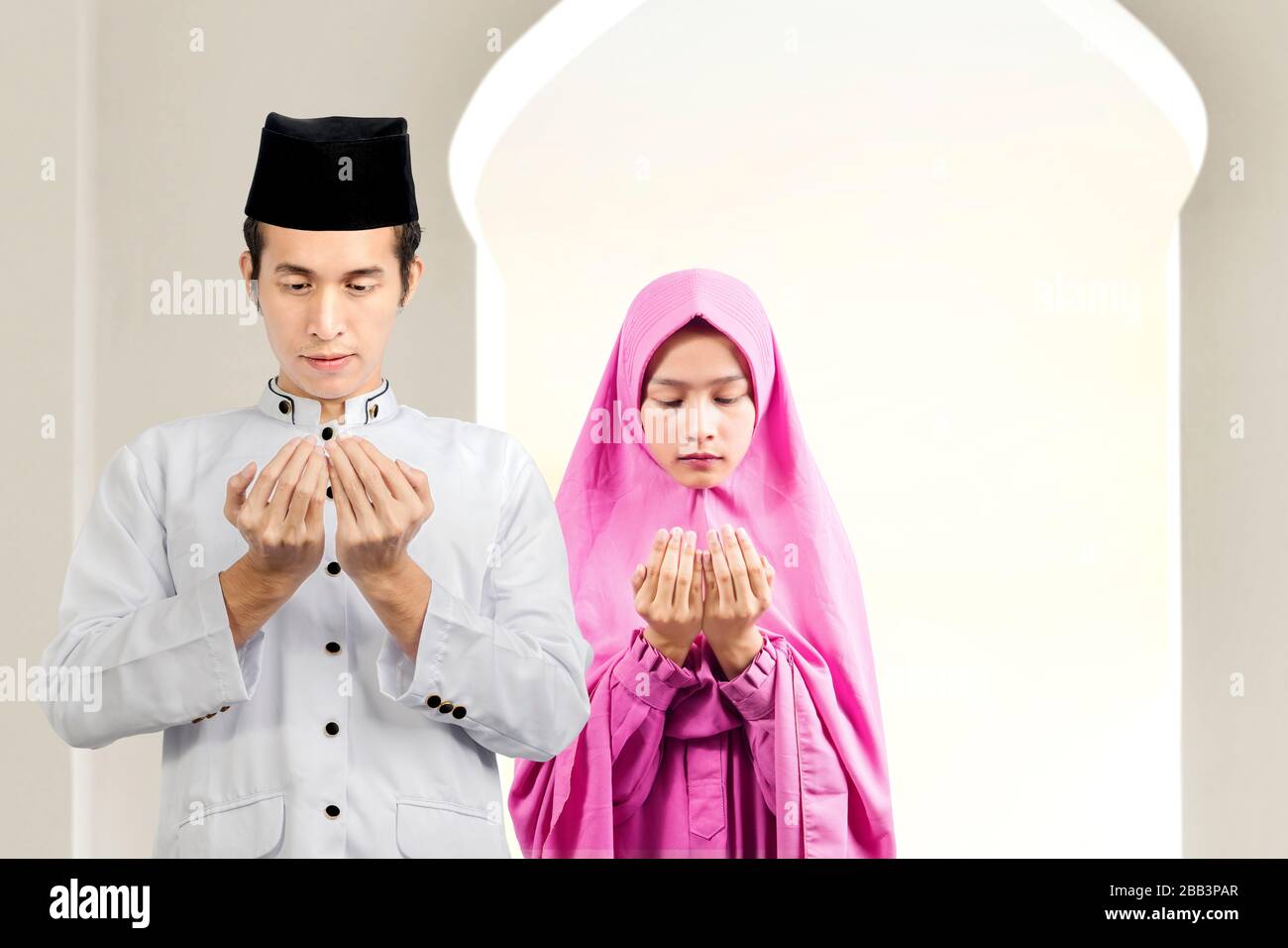 Asian Muslim couple standing while raised hands and praying together ...