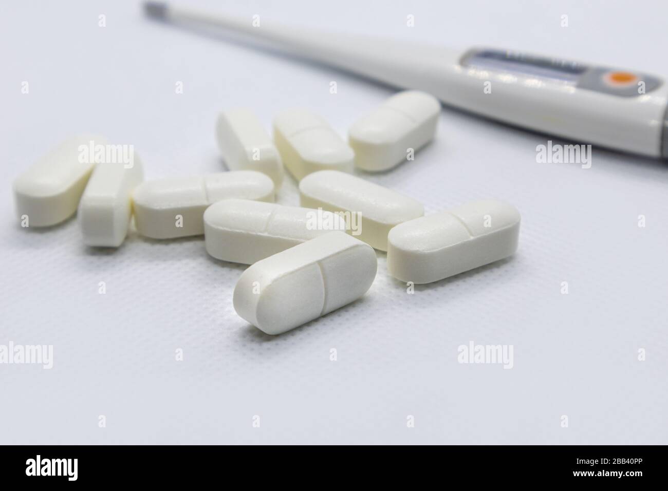 White long pills on white thermometer background. Cure medicine health ...