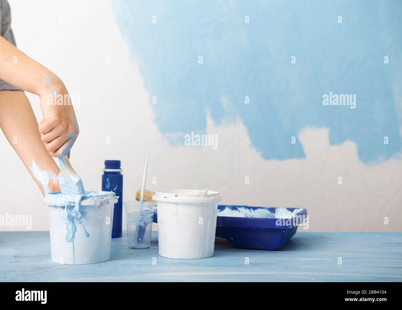 Homemade repair. Girls hand mixes blue paint Stock Photo - Alamy