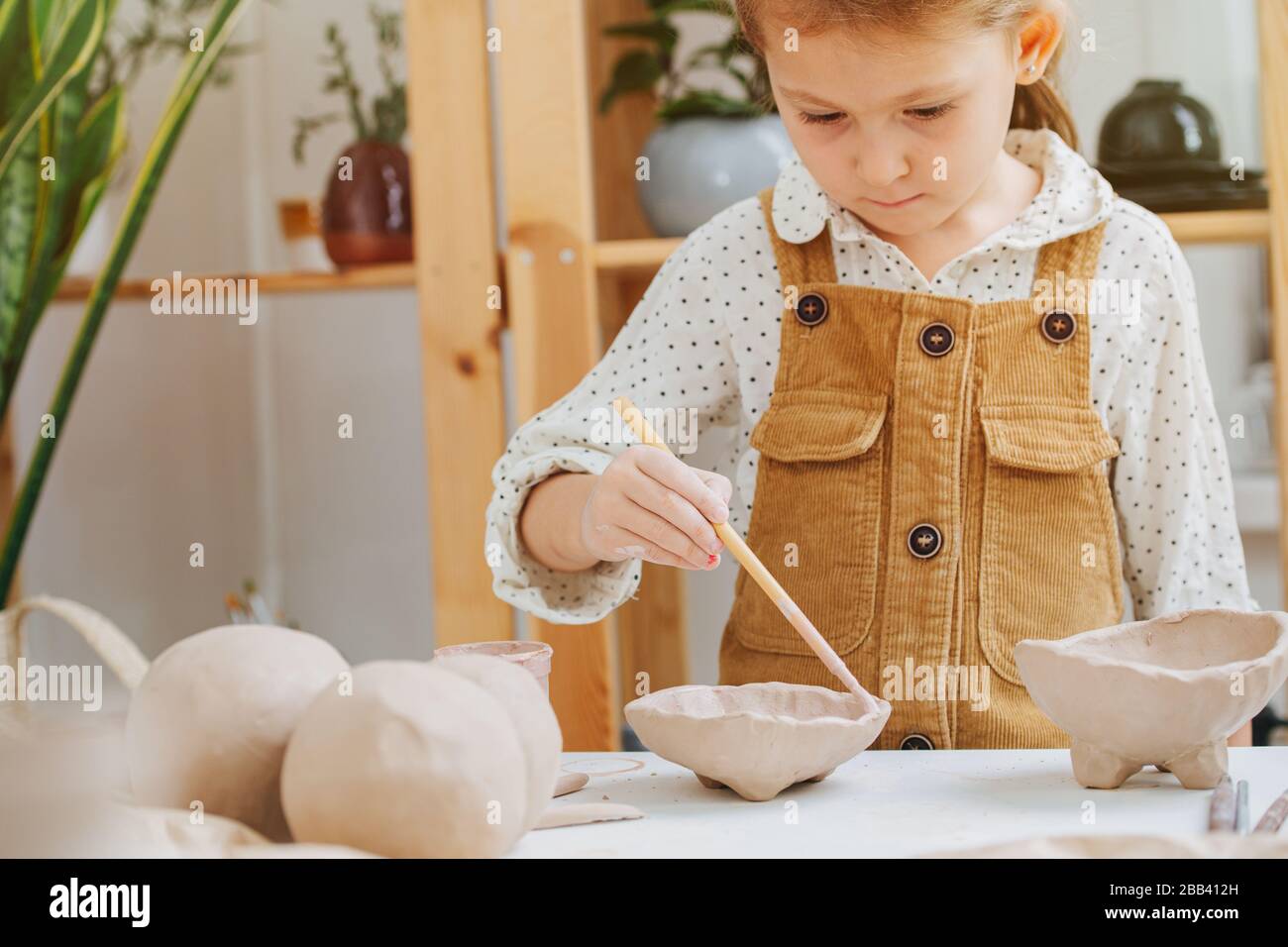 Girl is passionate about painting pottery against the background of the ...