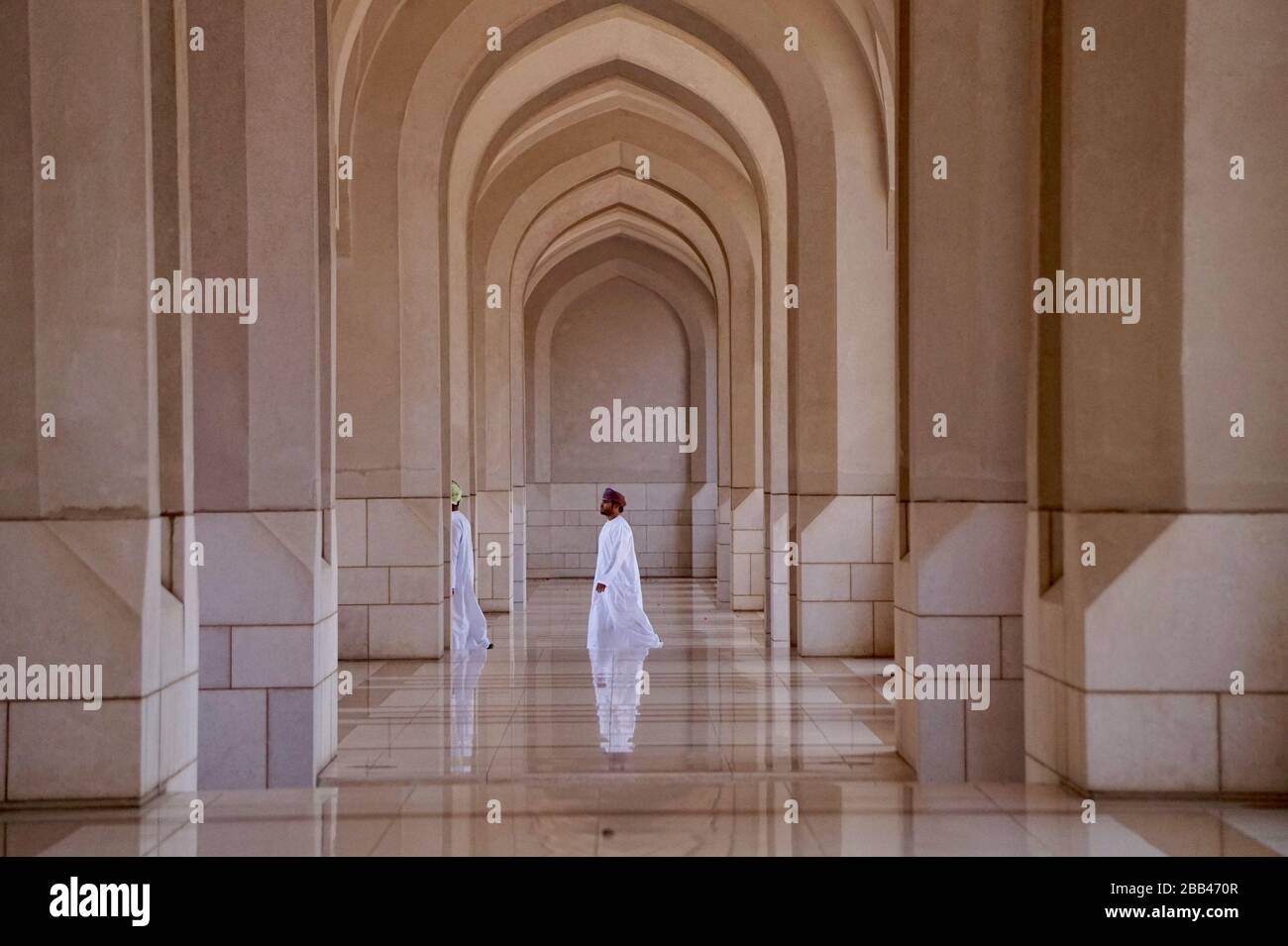 Two omani men walking past an arch in a palace Stock Photo - Alamy