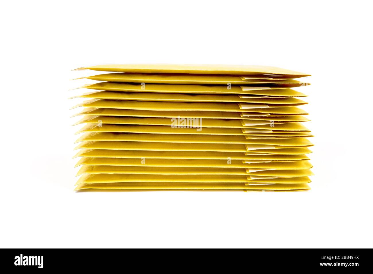 Stack of fifteen yellow bubble envelopes isolated on white, side view ...