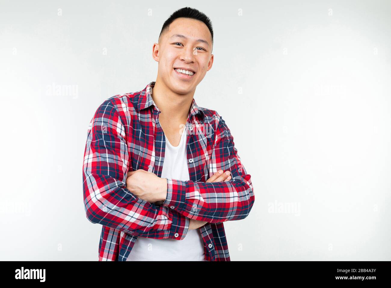 Confident Asian man in a plaid shirt wide open on a white studio ...