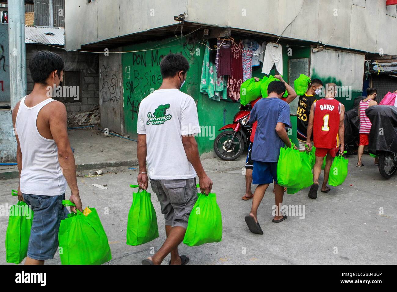 Quezon City. 30th Mar, 2020. Volunteers carry bags of relief goods as ...