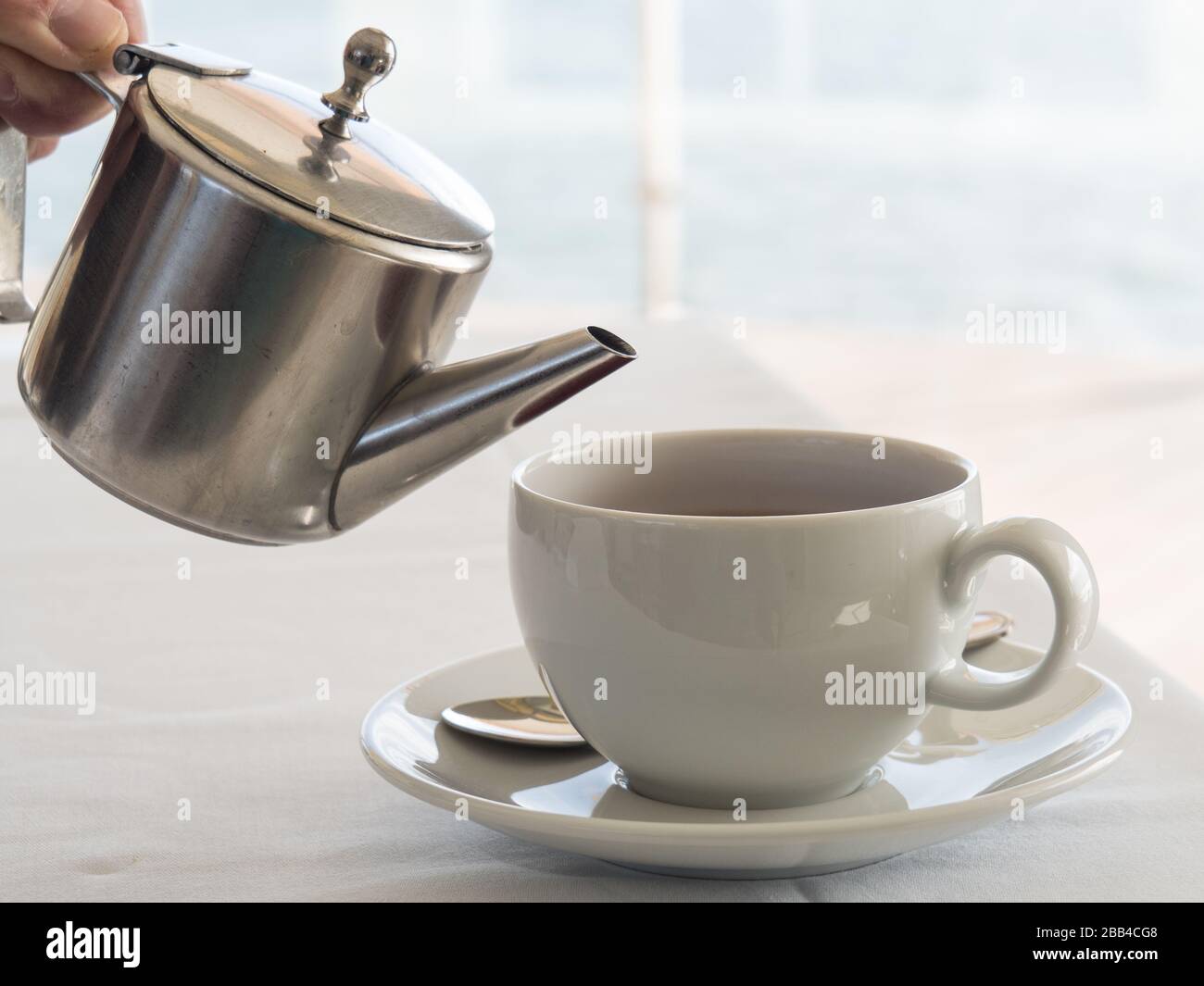 caucasian hand pouring tea from silver metal teapot Stock Photo - Alamy