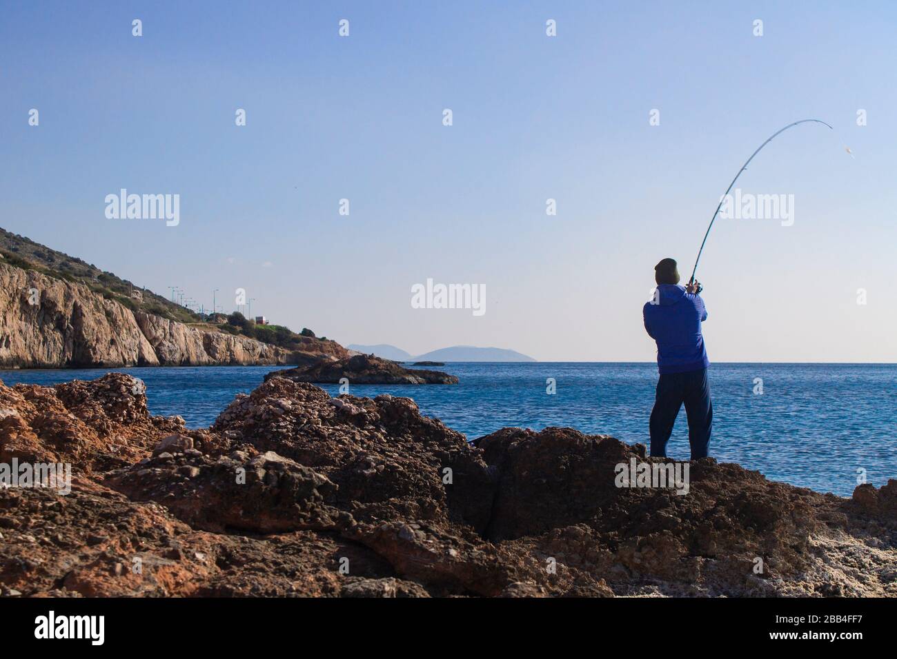 Unrecognizable fisherman a man stands on the sea shore with rocks and ...