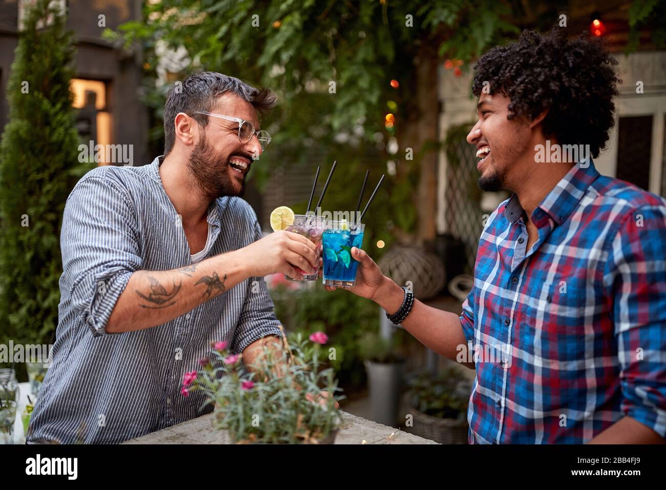 Two male friends tap with glasses in cafe Stock Photo - Alamy