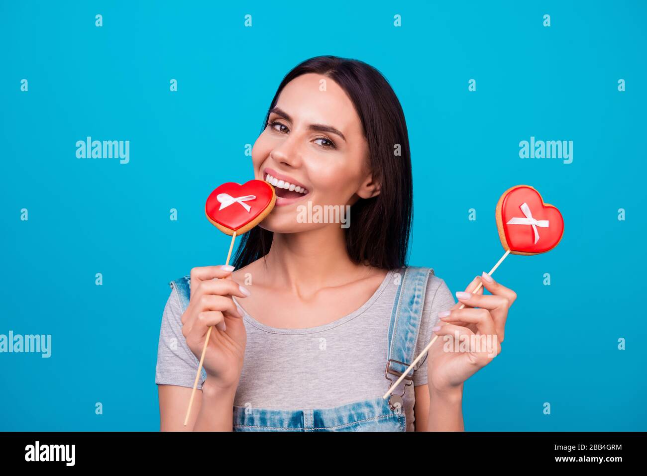 Yummy! Charming young brunette with red candies hearts on bright blue ...