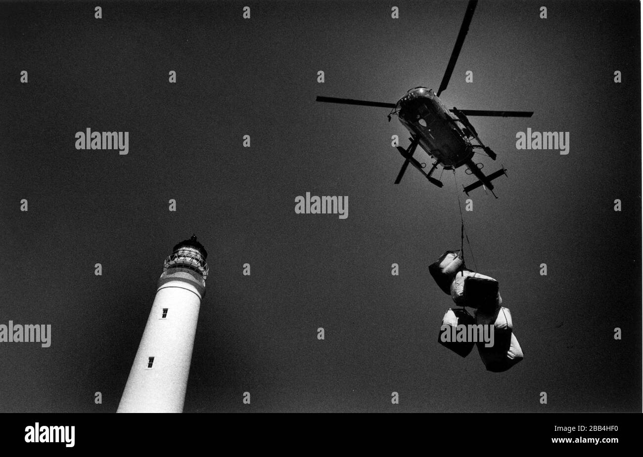 A supply helicopter flies over the lighthouse on the uninhabited island ...