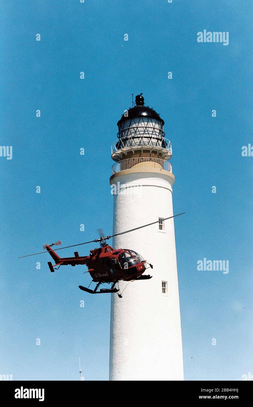 A supply helicopter flies over the lighthouse on the uninhabited island ...