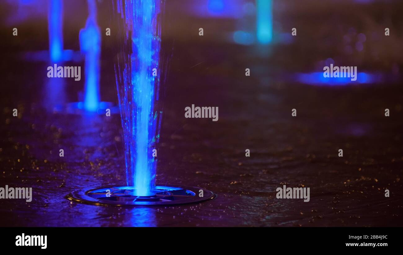 Splashes of colorful fountain. Water illuminated in diverse colors ...