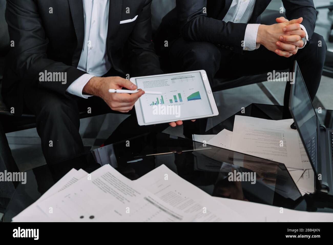 Close up businessman consulting client, holding document with graphs ...