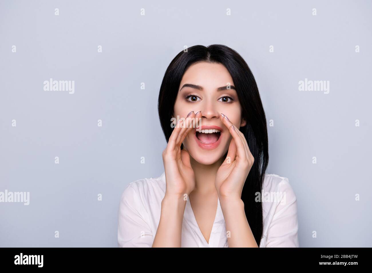 Hey! Cheerful young lady in white casual shirt is shouting and holding ...