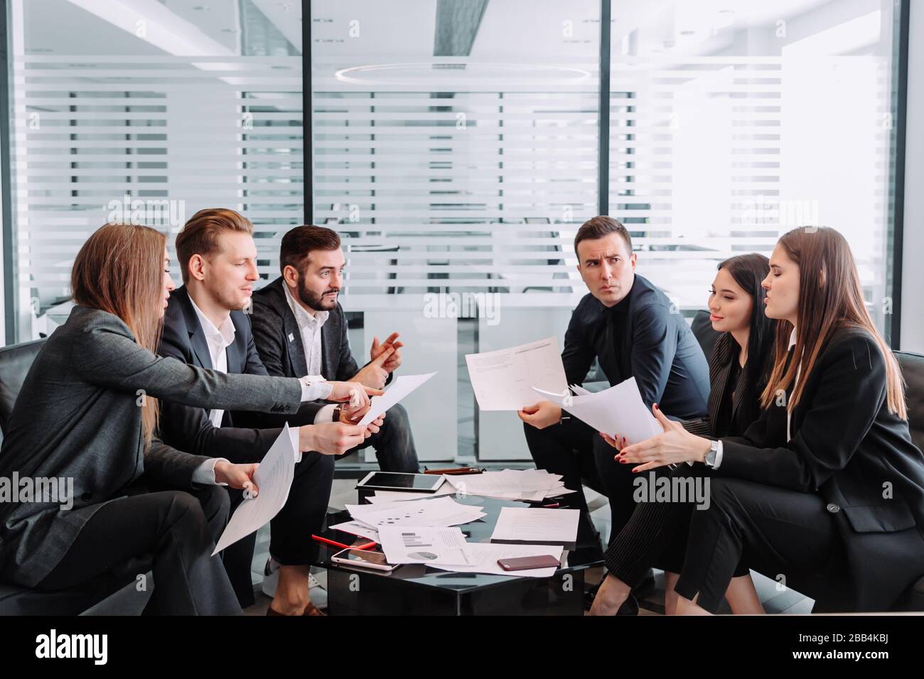 Male and female professionals having discussion at table in new office ...