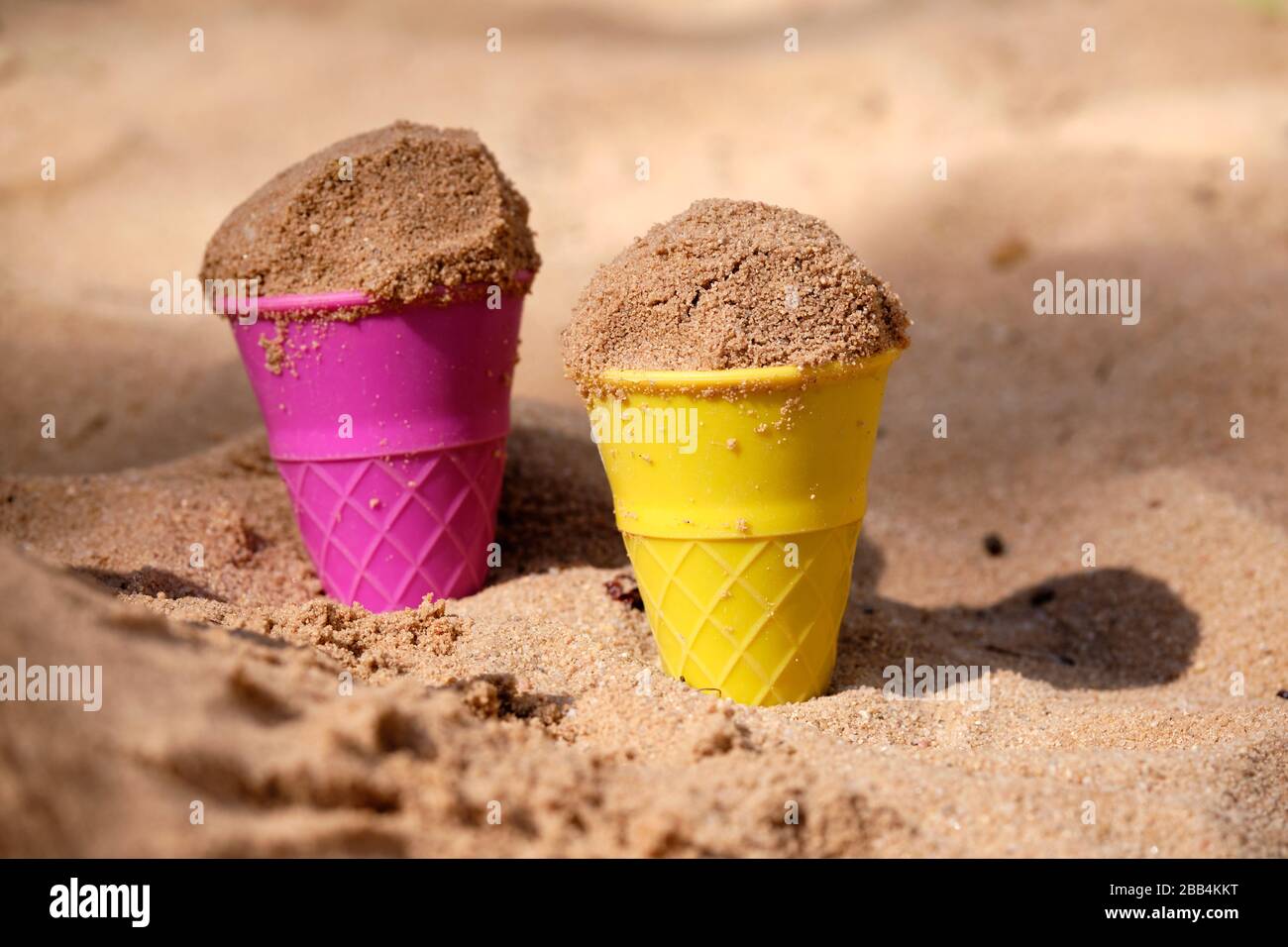 Closeup of two colorful sand moulds in shape of ice cream cones with ...