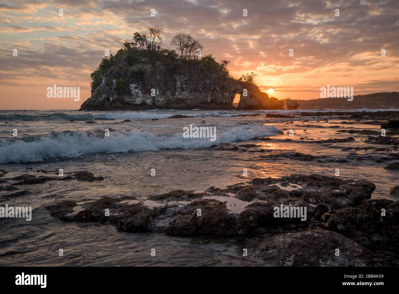 Crystal Bay at low tide with the sunset through the rock island, sea ...