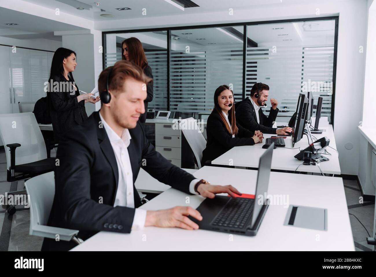Smiling call center employees sit in line with a headset Stock Photo ...
