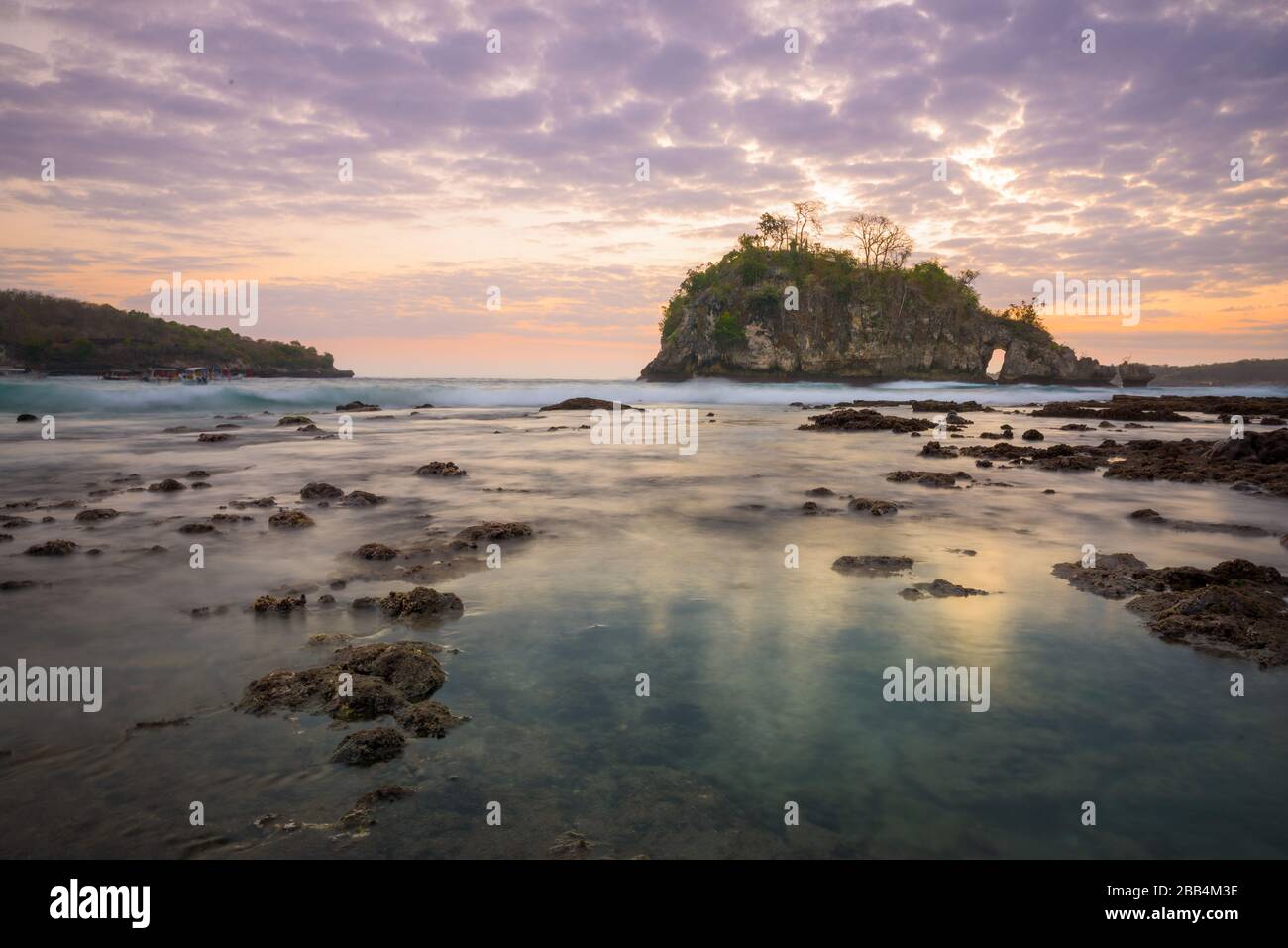 Crystal Bay at low tide with the sunset through the rock island, sea ...