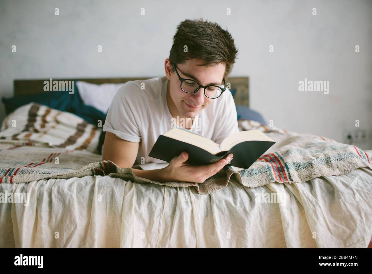 Man reading a book on his bed at home Stock Photo - Alamy