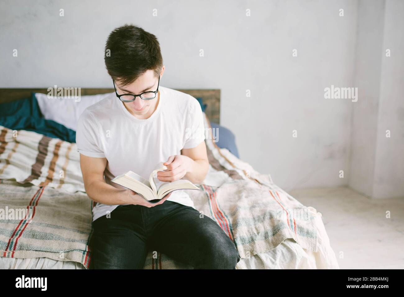 Man reading a book on his bed at home Stock Photo - Alamy