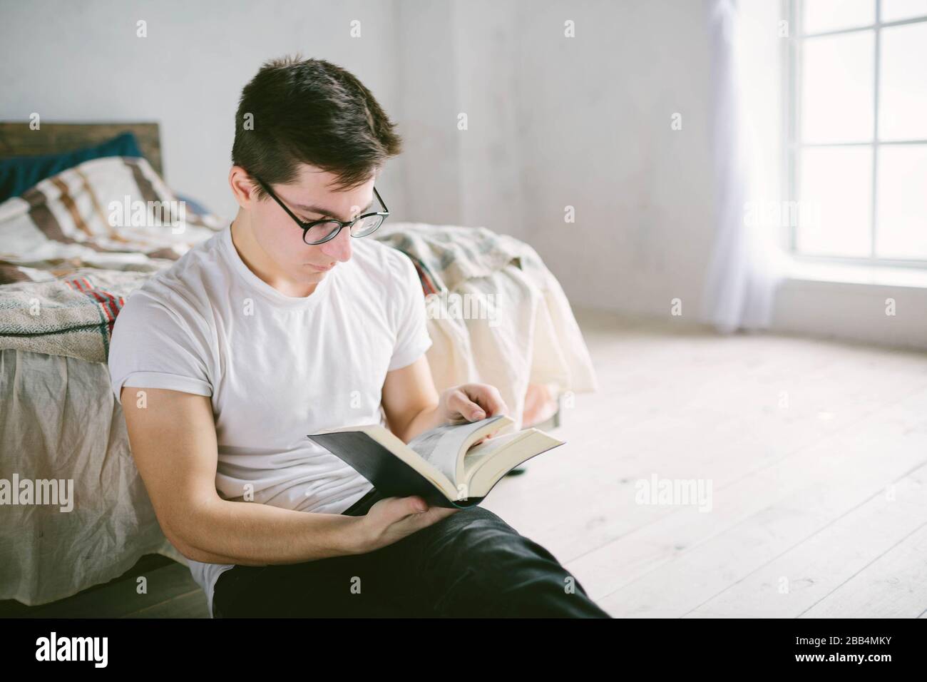 Man reading a book on his bed at home Stock Photo - Alamy