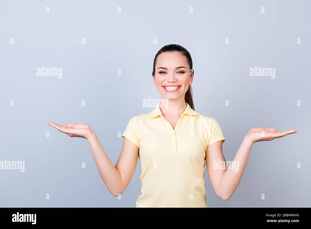 Cheerful charming girl in casual tshirt on pure background is gesturing ...