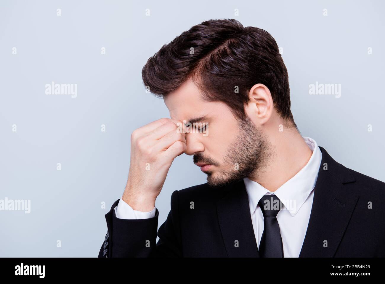 Side view portrait of sad man in formal clothes touching his nose ...