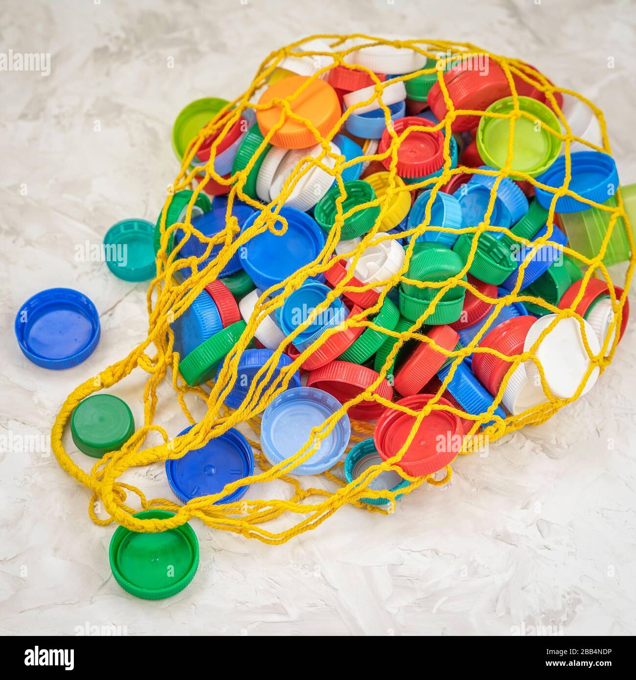 Colorful plastic caps ready in mesh string bag. Concept of recycling ...