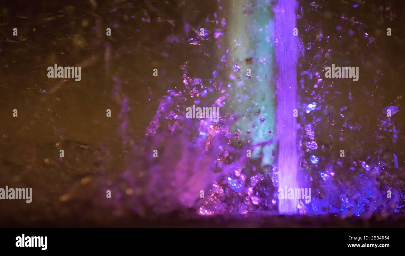 Splashes of colorful fountain. Water illuminated in diverse colors ...