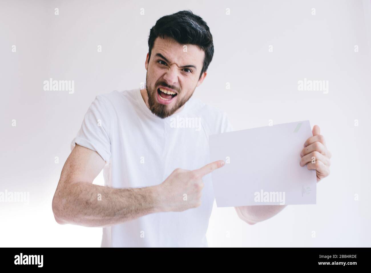 Bearded man holding a blank white sheet of paper. Angry young guy ...