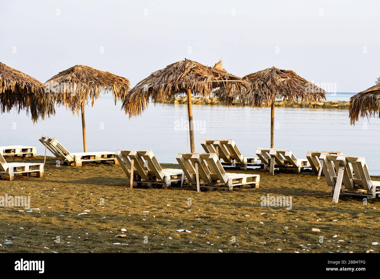 Rustic beach sunbeds and umbrellas Stock Photo - Alamy