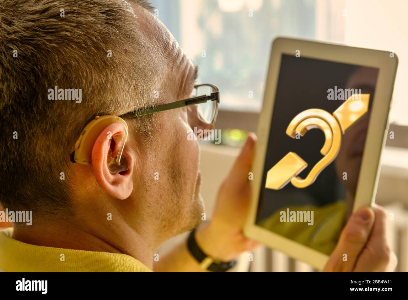 Man wearing deaf aid in ear with tablet showing deaf sign an the ...