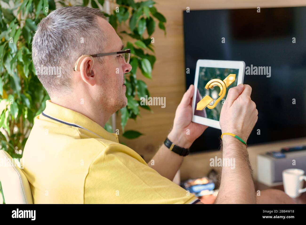 Man wearing deaf aid in ear with tablet showing deaf sign an the ...