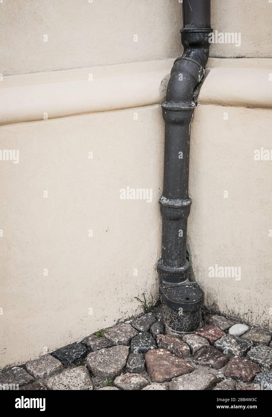 Vertical shot of a pipe going in front of a wall into the ground Stock ...