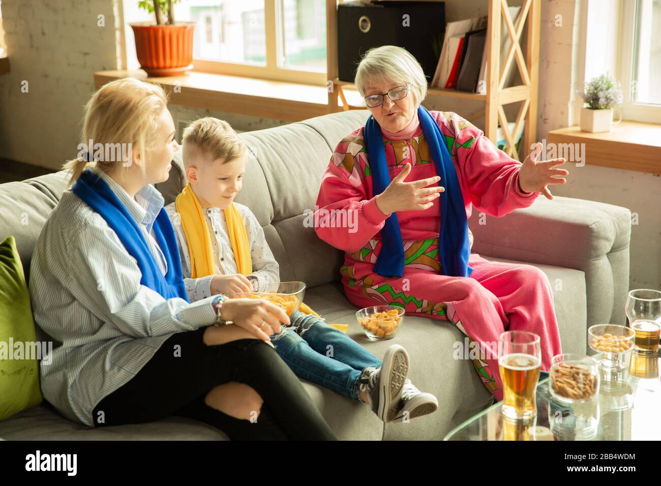 Excited family watching football, sport match at home. Grandma, mother ...