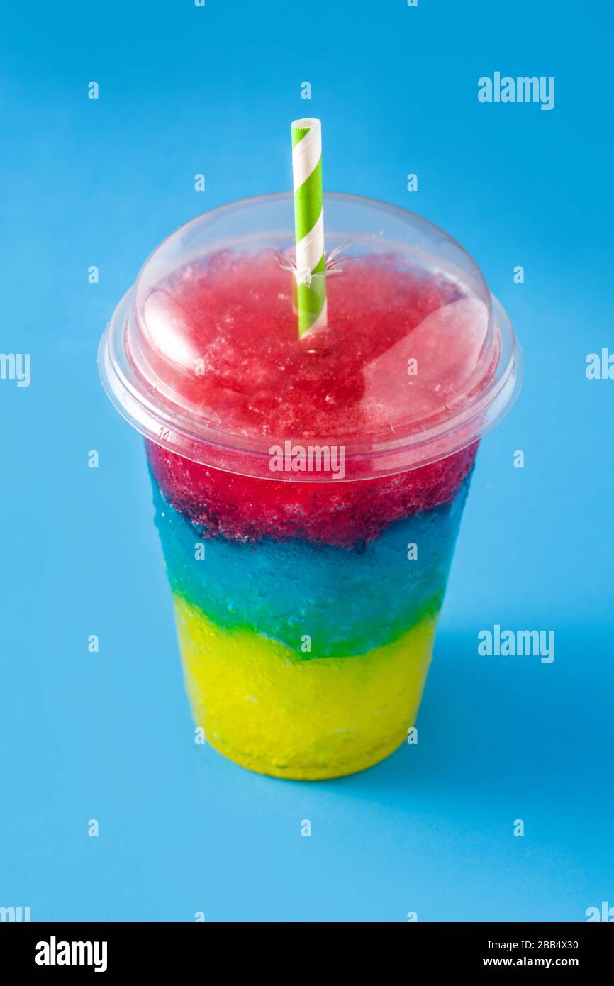Colorful slushie of differents flavors with straw on blue background ...