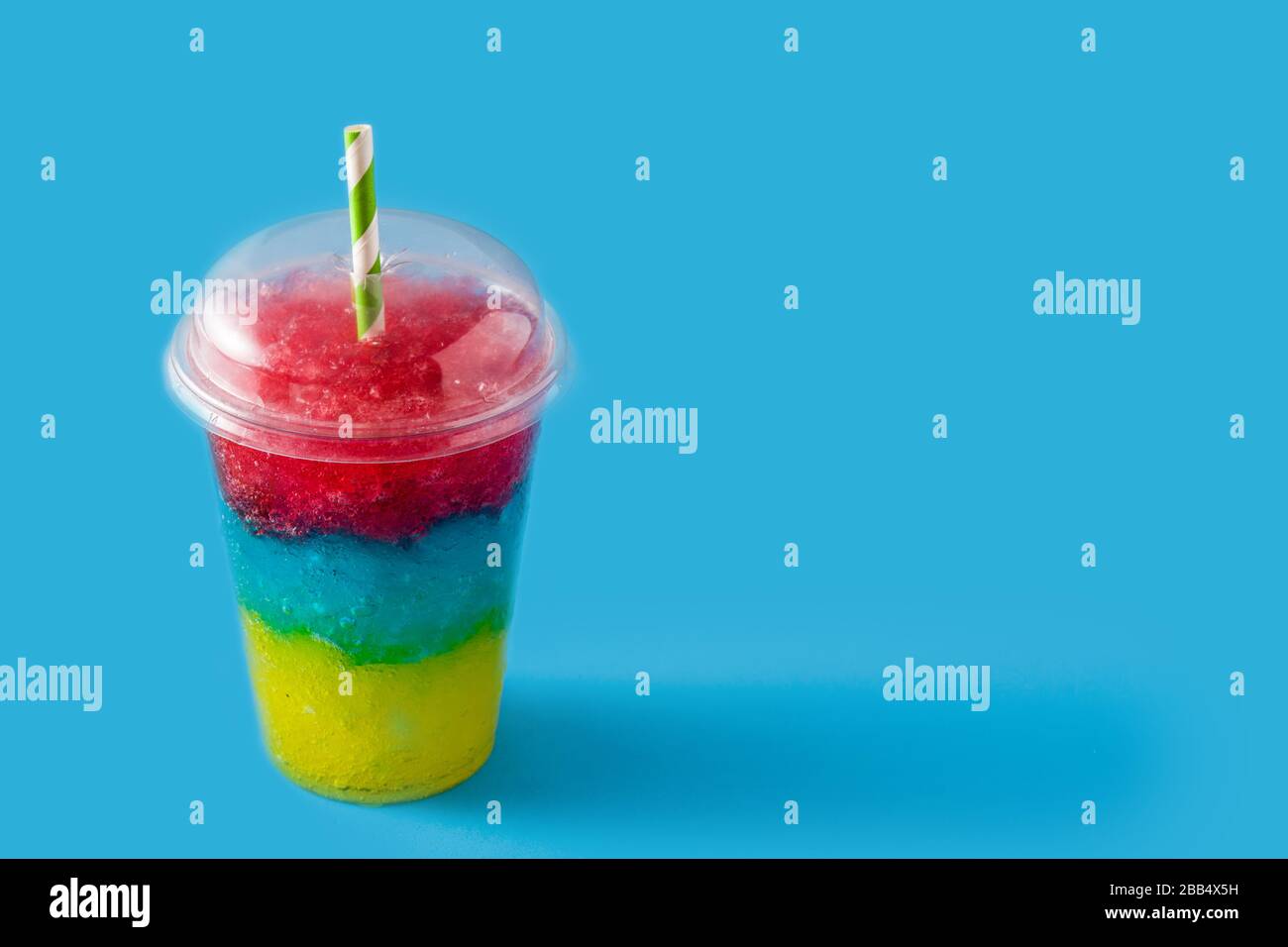Colorful slushie of differents flavors with straw on blue background ...