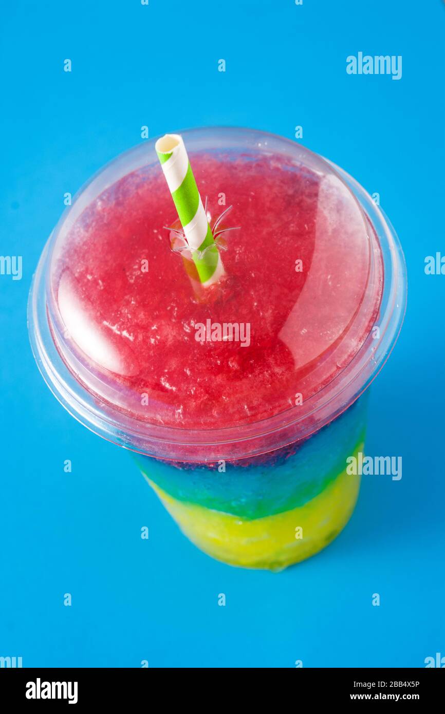 Colorful slushie of differents flavors with straw on blue background ...
