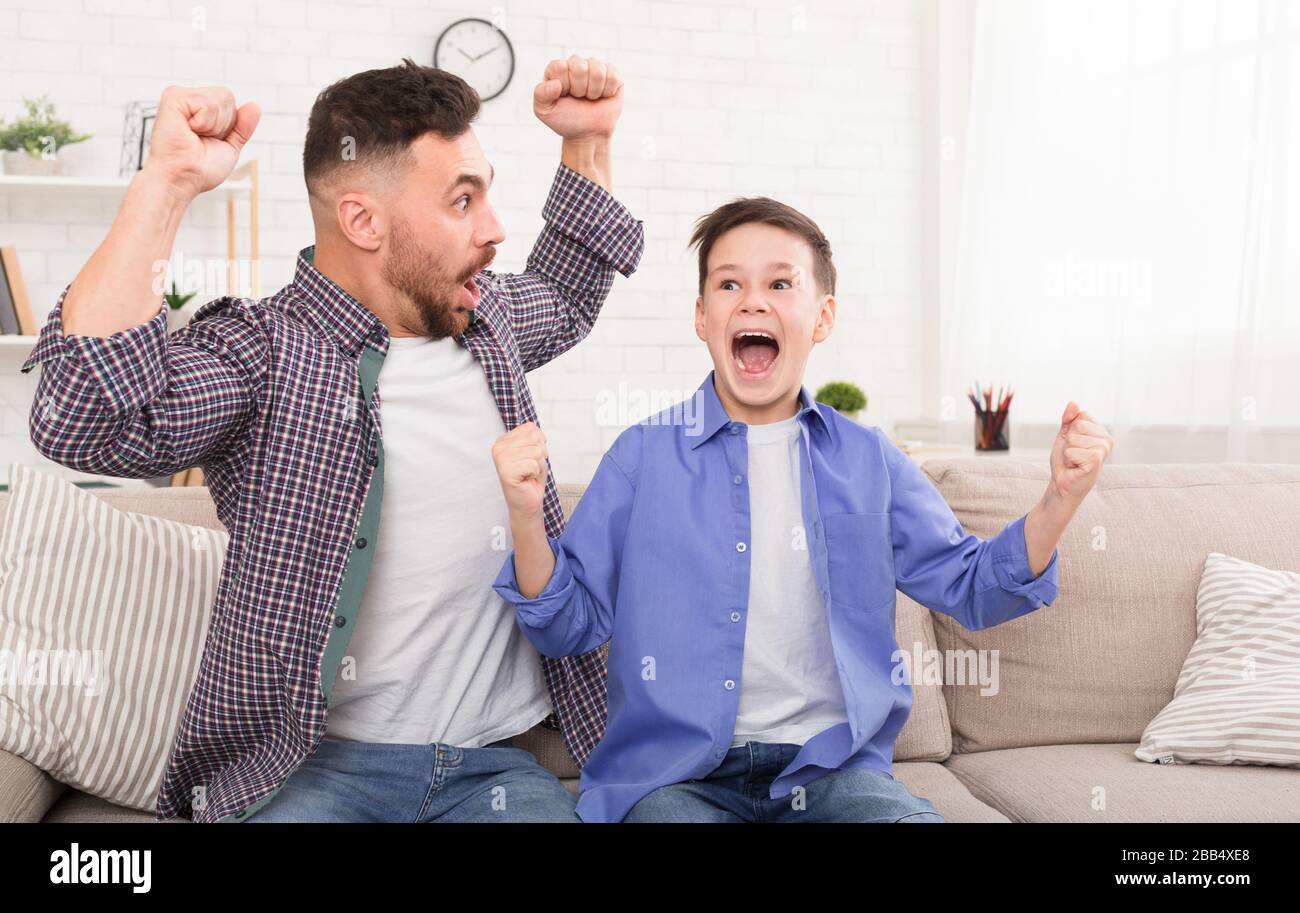 Emotional dad and son watching tv at home, free space Stock Photo - Alamy